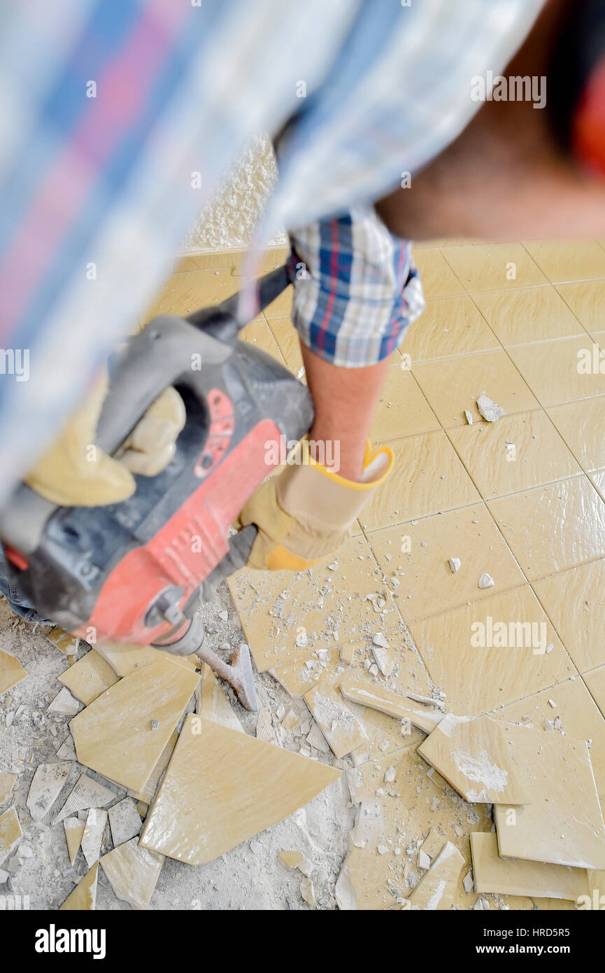 Builder breaking up floor tiles with a machine Stock Photo - Alamy