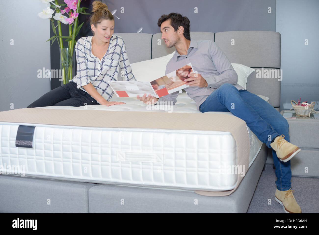 Couple sat on new bed looking at brochure Stock Photo - Alamy