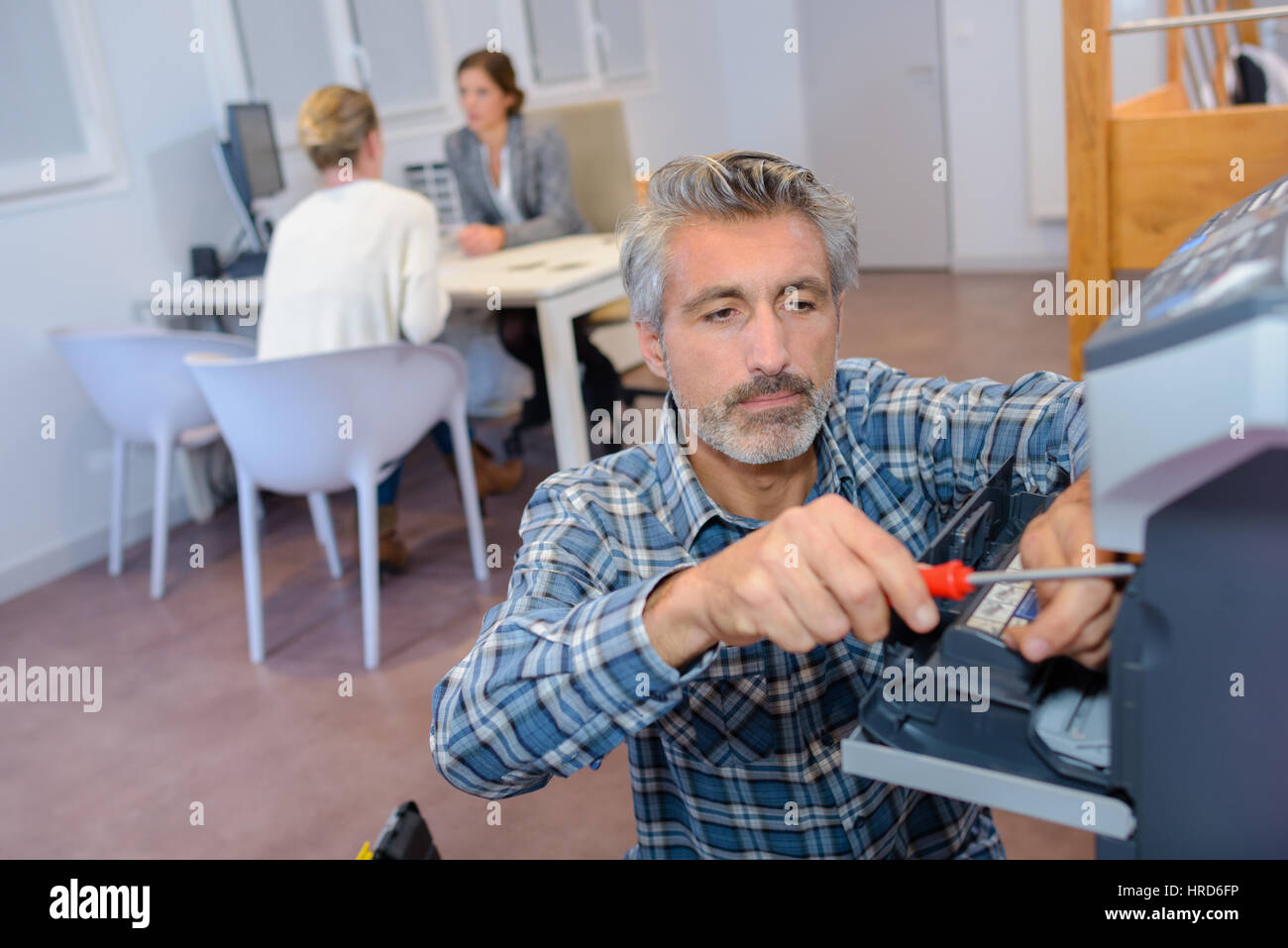 company handyman fixing a printer Stock Photo - Alamy