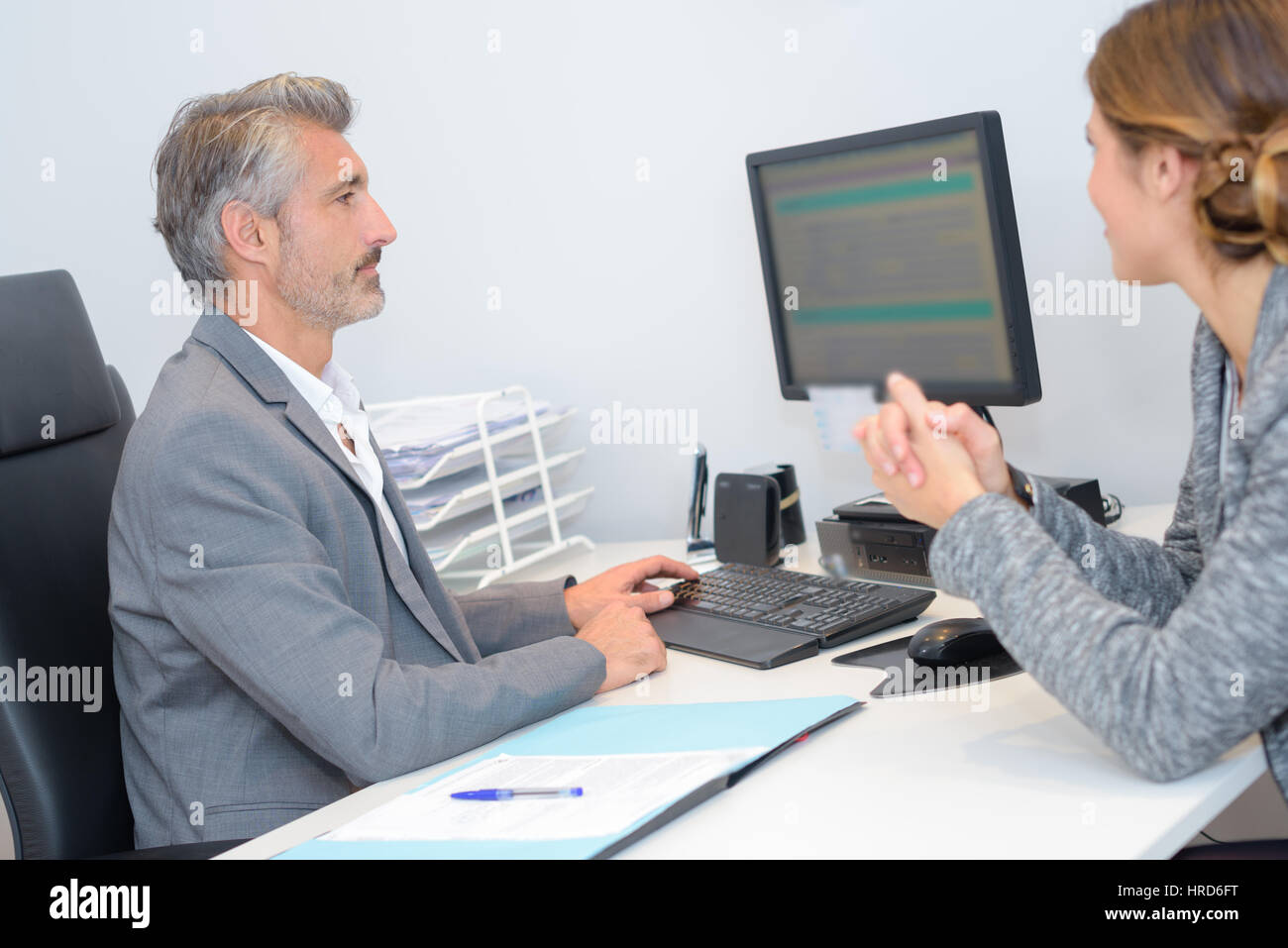 Man and woman in meeting looking at computer screen Stock Photo - Alamy