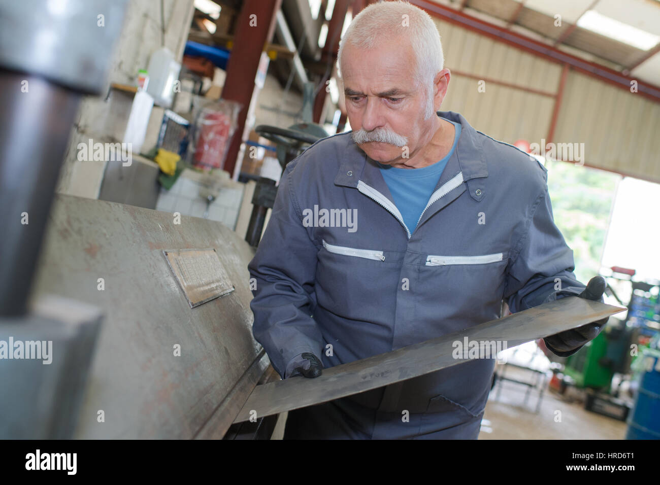 Man feeding metal into machine Stock Photo - Alamy