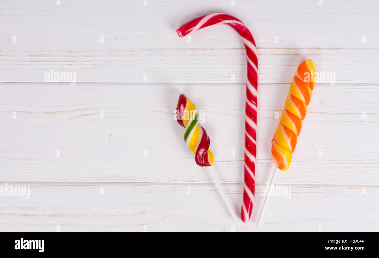 Tasty candy cane and colorful bright lollipops on wooden white board ...