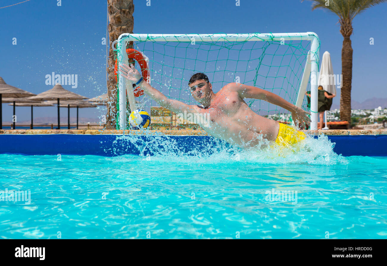Young man in action skips the goal in pool playing water polo at the ...