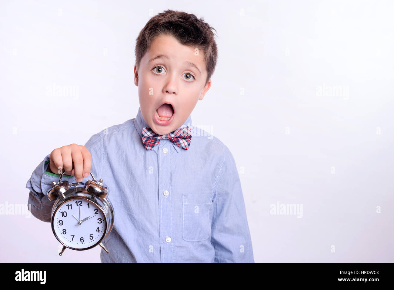 Surprised boy showing an alarm clock for time playful Stock Photo - Alamy
