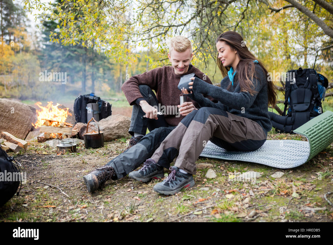 Full length of young couple making coffee on campsite in forest Stock ...