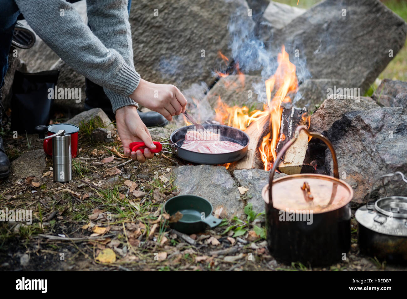 Cropped image of man cooking food over bonfire at campsite Stock Photo ...