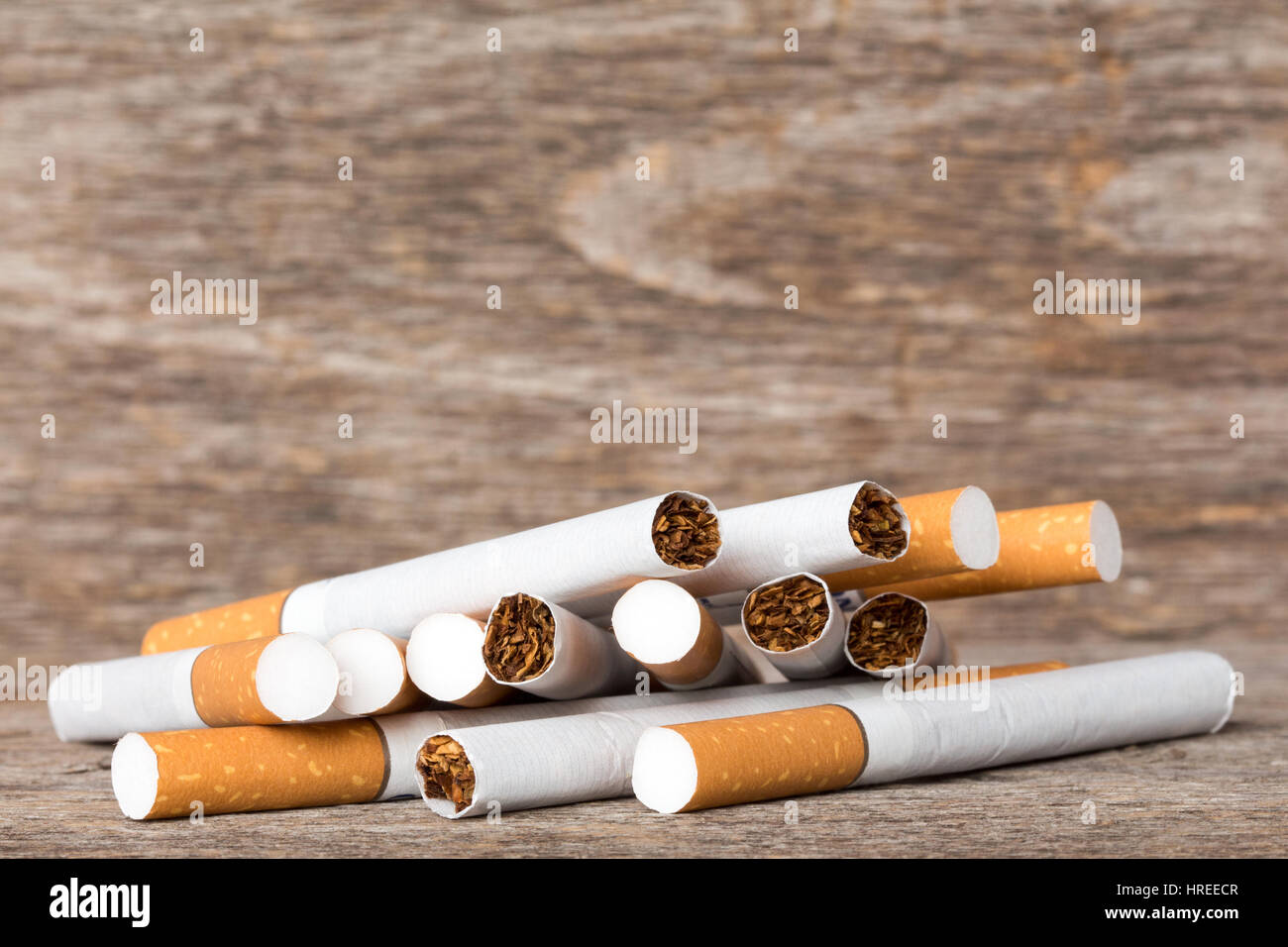 Pile of cigarettes scattered on wooden background Stock Photo - Alamy