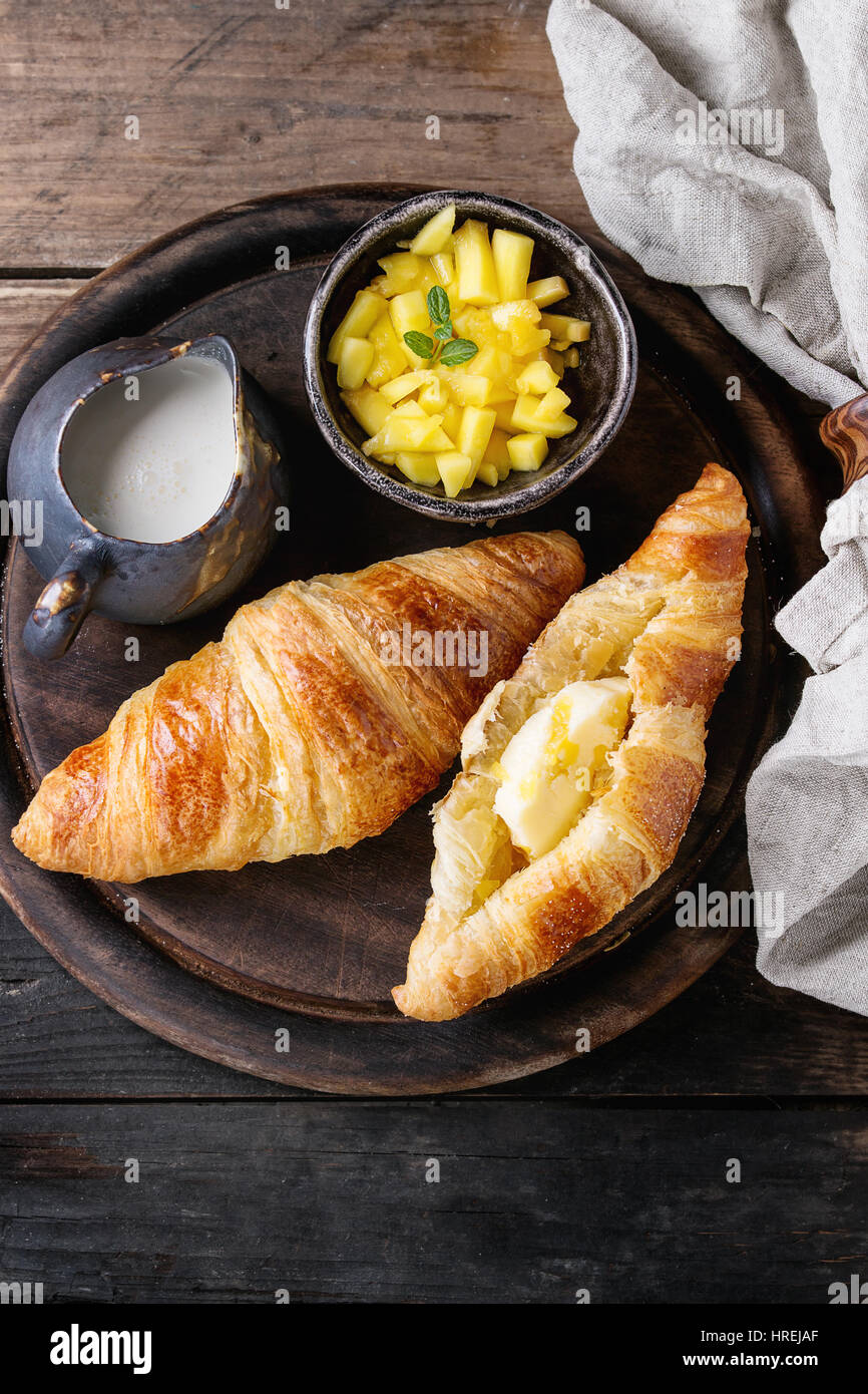 Breakfast with two croissant, butter, cream and sliced mango fruit ...