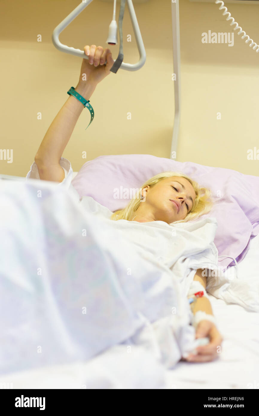Bedridden female patient lying in hospital bed, recovering after ...