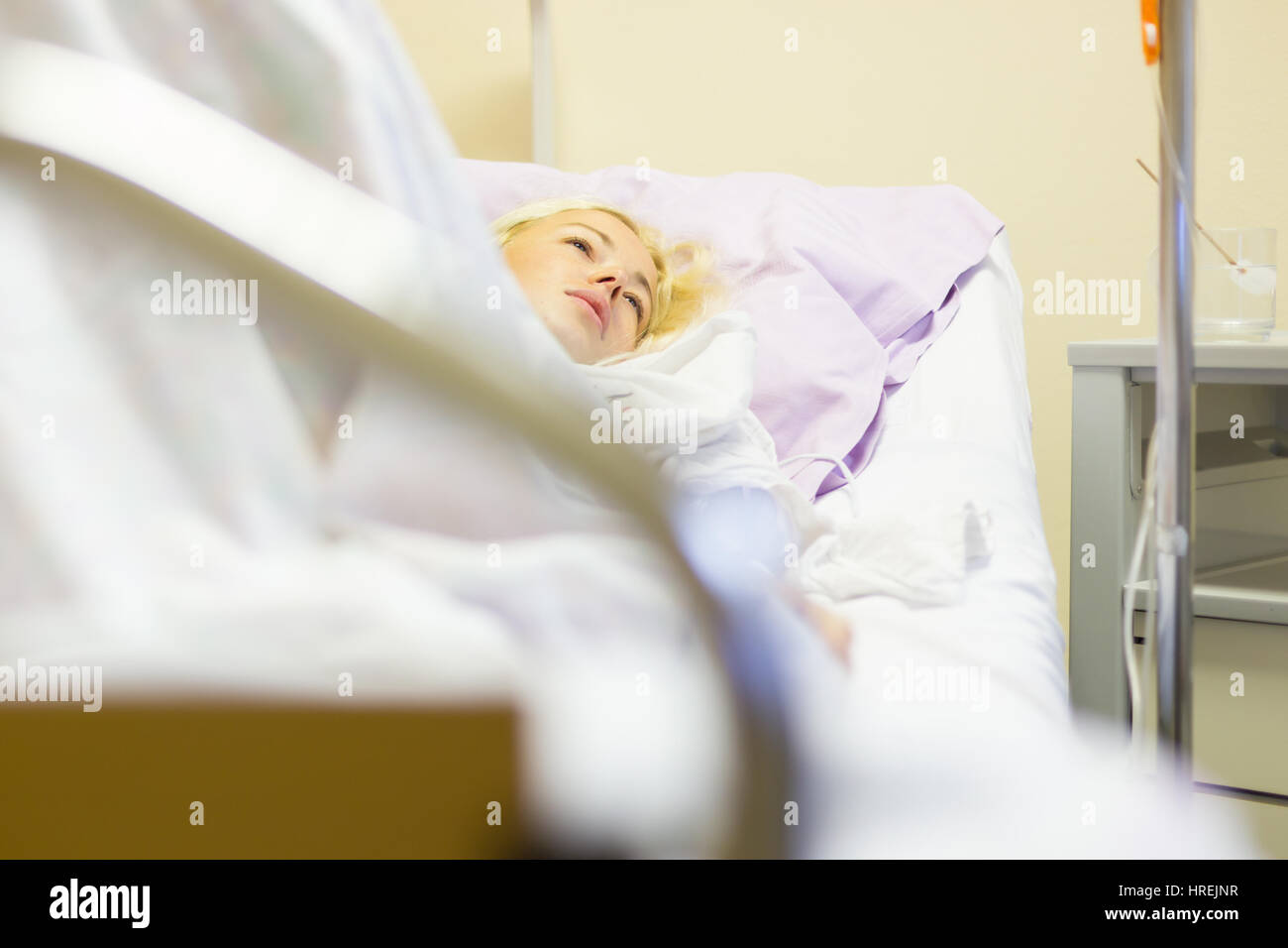 Bedridden female patient lying in hospital bed, recovering after ...