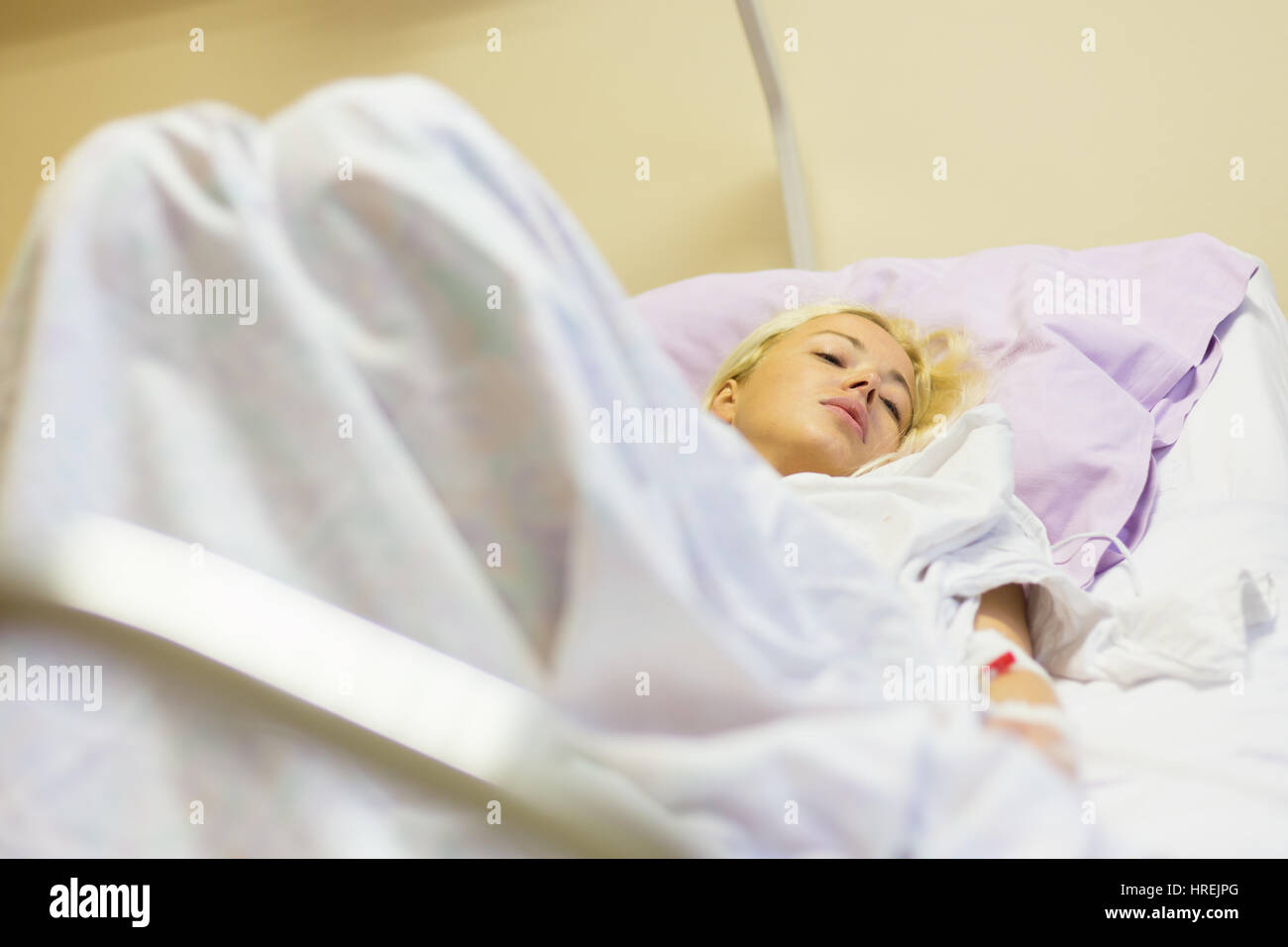 Bedridden female patient lying in hospital bed, recovering after ...