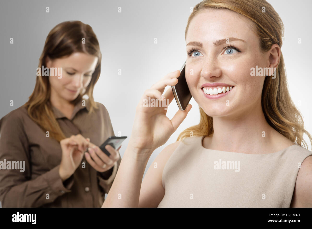 two business women one in front of the other talking on a mobile phone ...