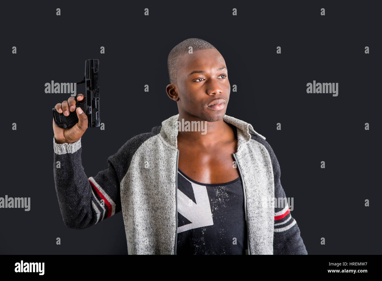 Young handsome black man holding a hand gun, on dark background in ...