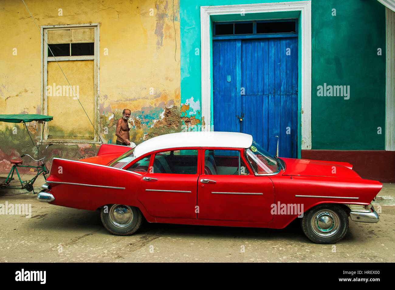 A man walking near a classical red limousine of 50' years parked in ...