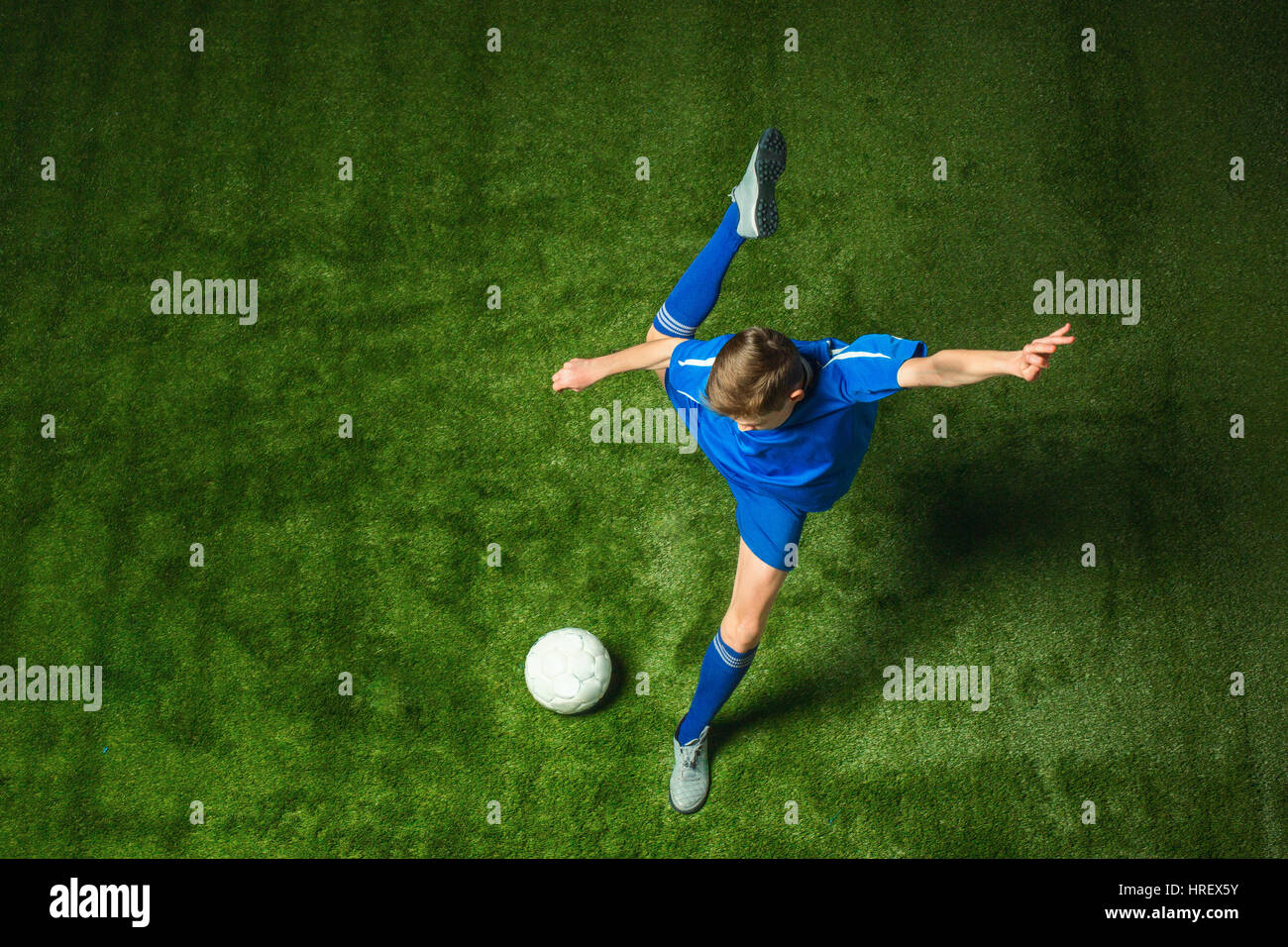 Young boy with soccer ball doing flying kick, on green studio ...