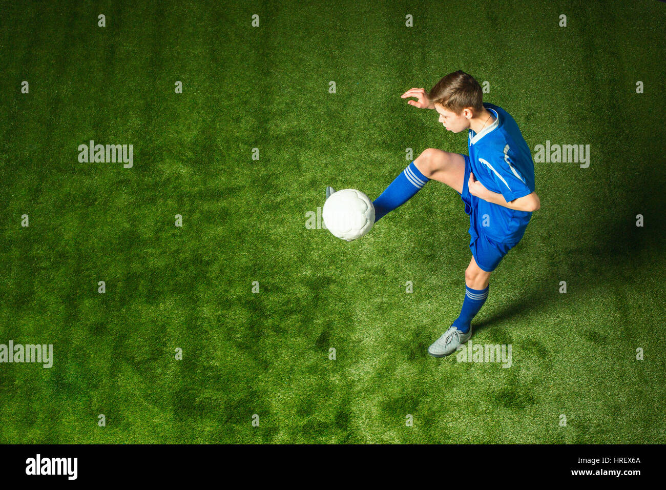Young boy with soccer ball doing flying kick, on green studio ...