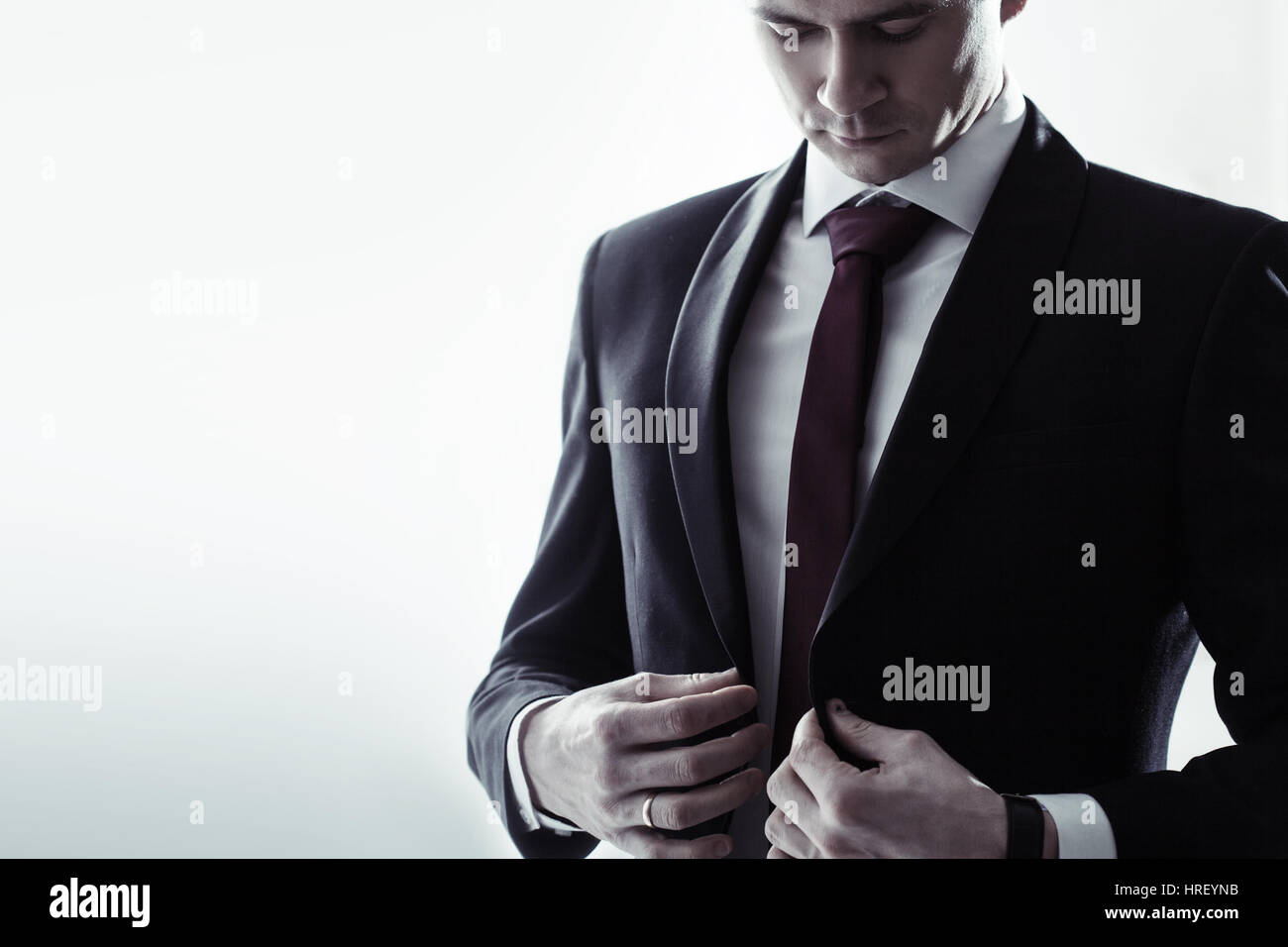 A young man in a tuxedo with a tie. Is adjusting his jacket Stock Photo ...