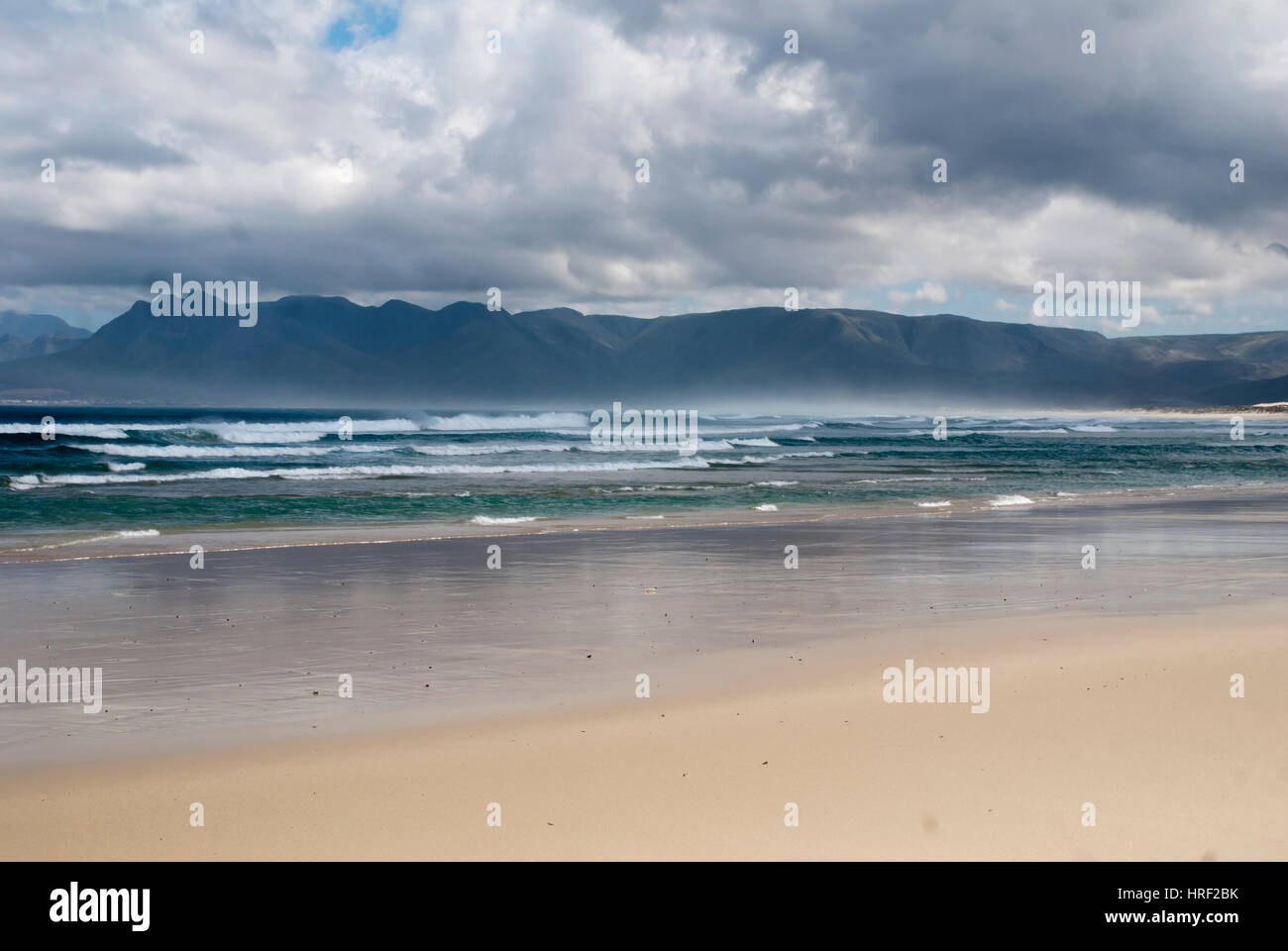 Rolling waves on a beach with mountains in the background on Hawston ...
