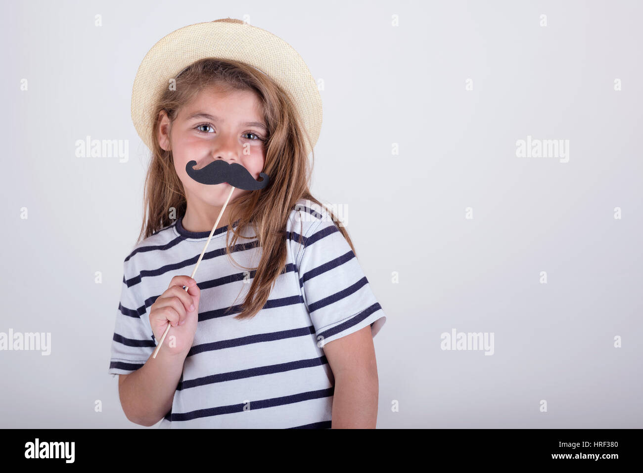Beautiful cute little girl playing with mustache Stock Photo - Alamy