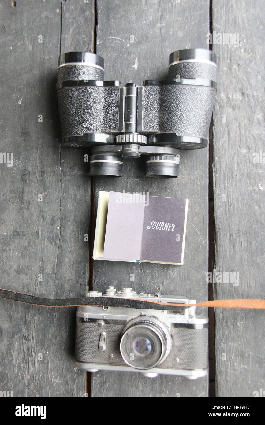 Journey vintage concept, binoculars and a camera a book on the table ...