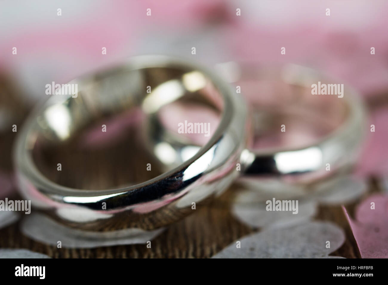 pair of white gold wedding rings on a wooden background with confetti ...