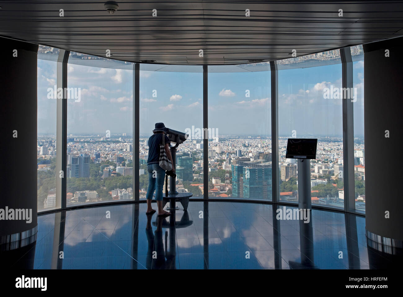 A tourist looking at the view from the Saigon Skydeck in the Bitexco ...