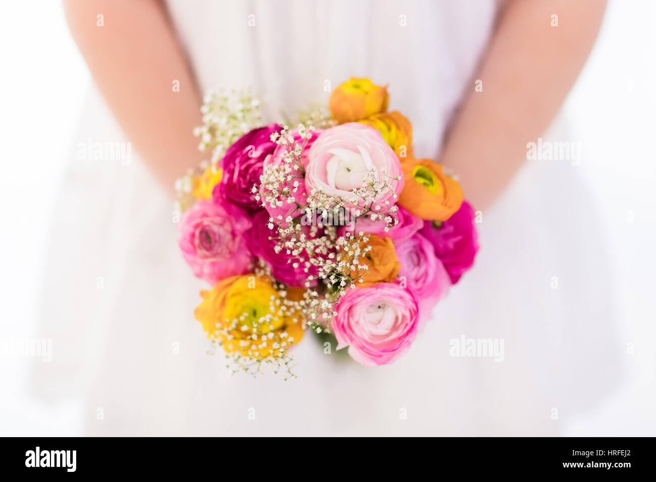 Cute little girl in white dress holding ranunculus flowers bouquet on ...
