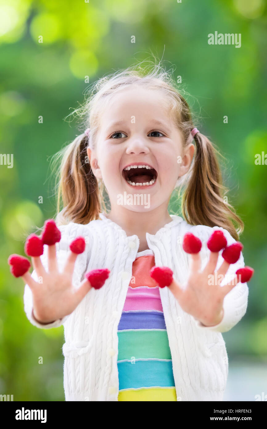 Child picking raspberry. Kids pick fresh fruit on organic raspberries ...