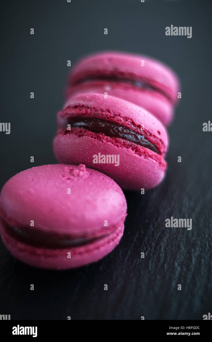 pink macaroons with raspberries on black background Stock Photo - Alamy