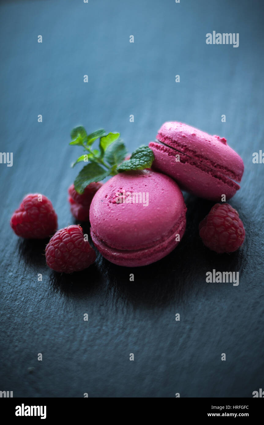 pink macaroons with raspberries on black background Stock Photo - Alamy