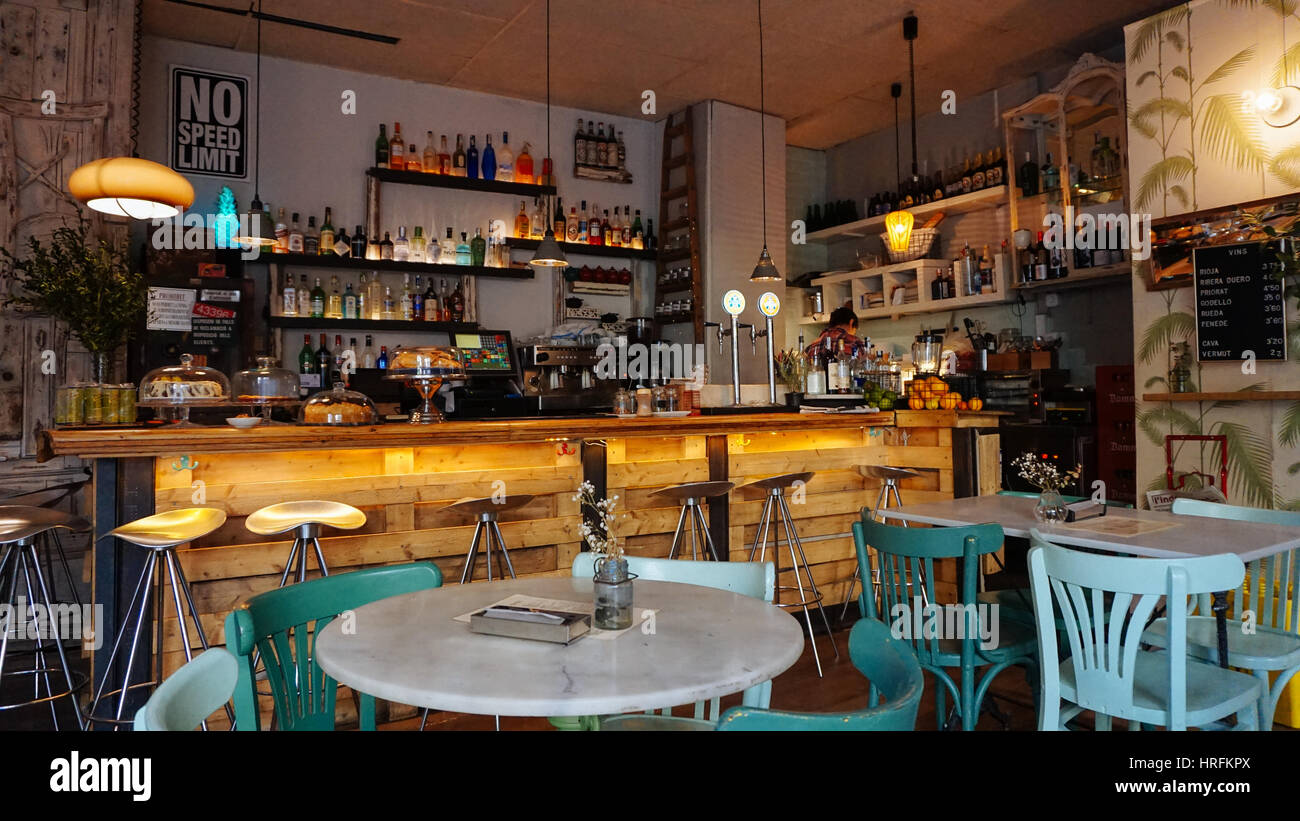 Inside a cafe with green chairs, white tables, and a bar with drinks ...