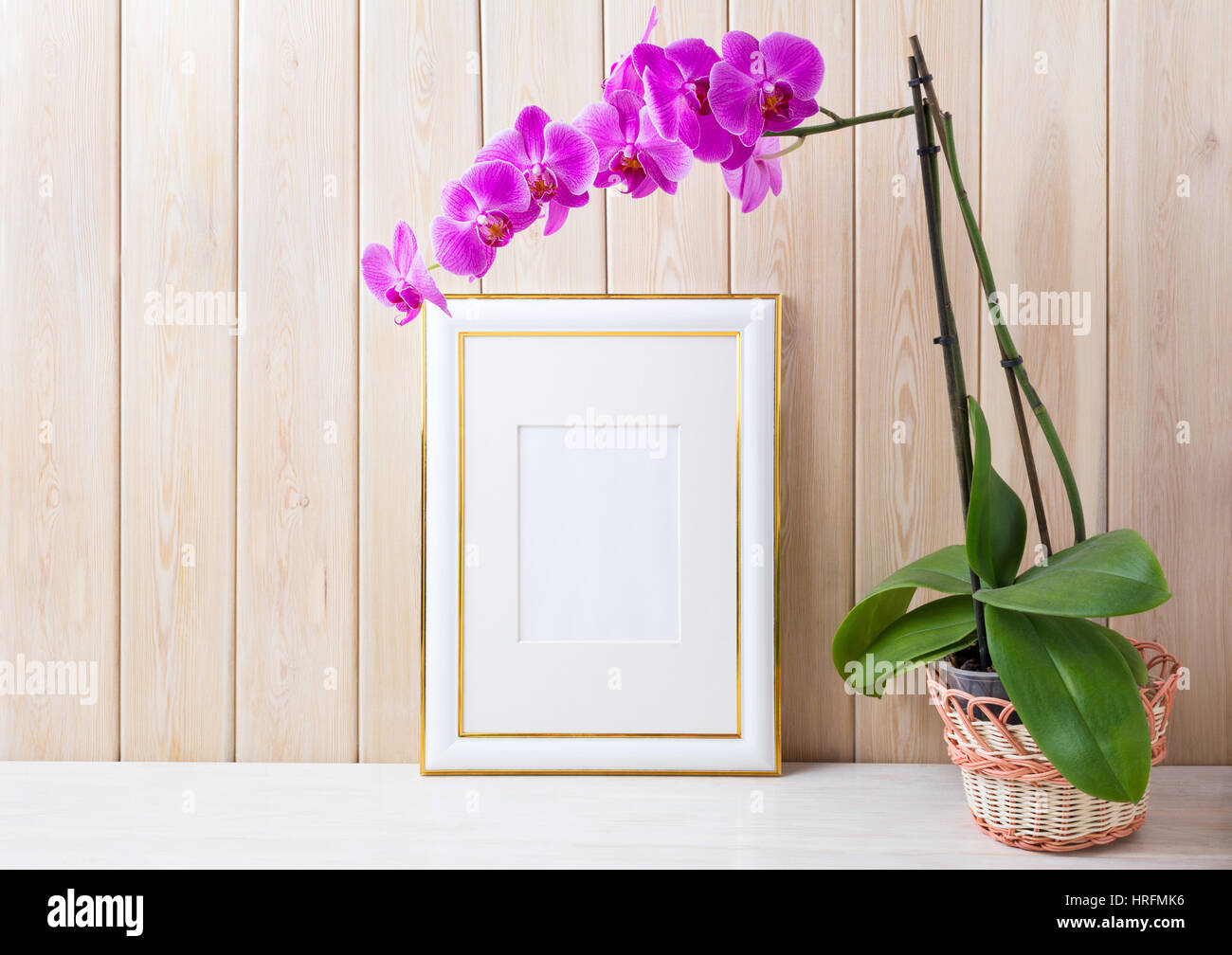 Gold decorated frame mockup with magenta-purple orchid in wicker basket ...