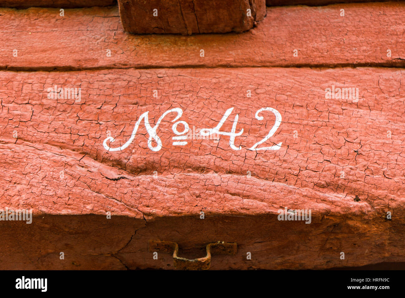 Number 42. wooden beam with cracked red paint and white Gothic numerals ...