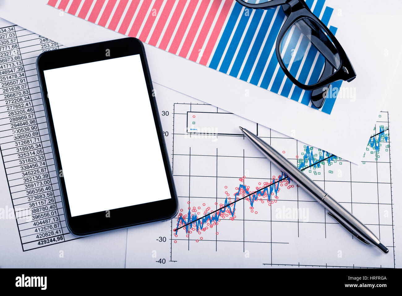 Smartphone on pile of papers and graphs Stock Photo - Alamy