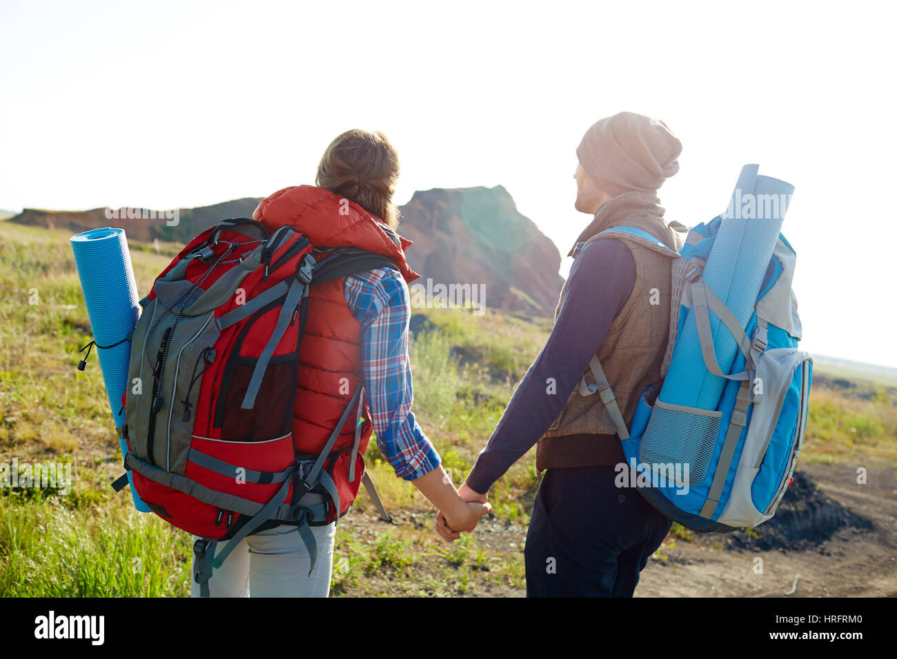 Rear view image of young tourist couple with big backpacks looking away ...