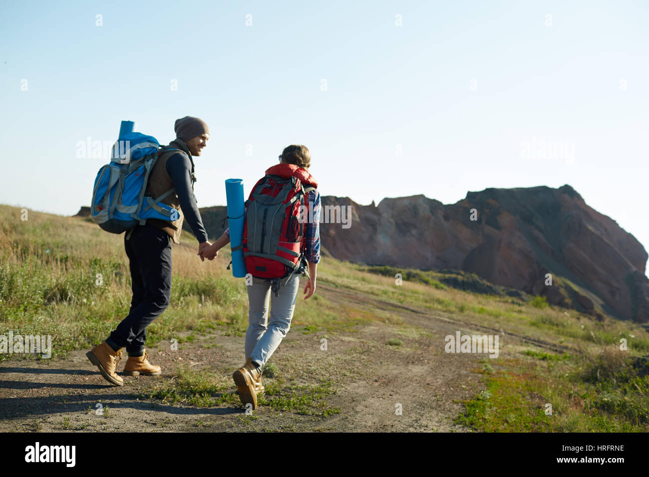 Rear view shot of young man and woman with big tourist backpacks ...