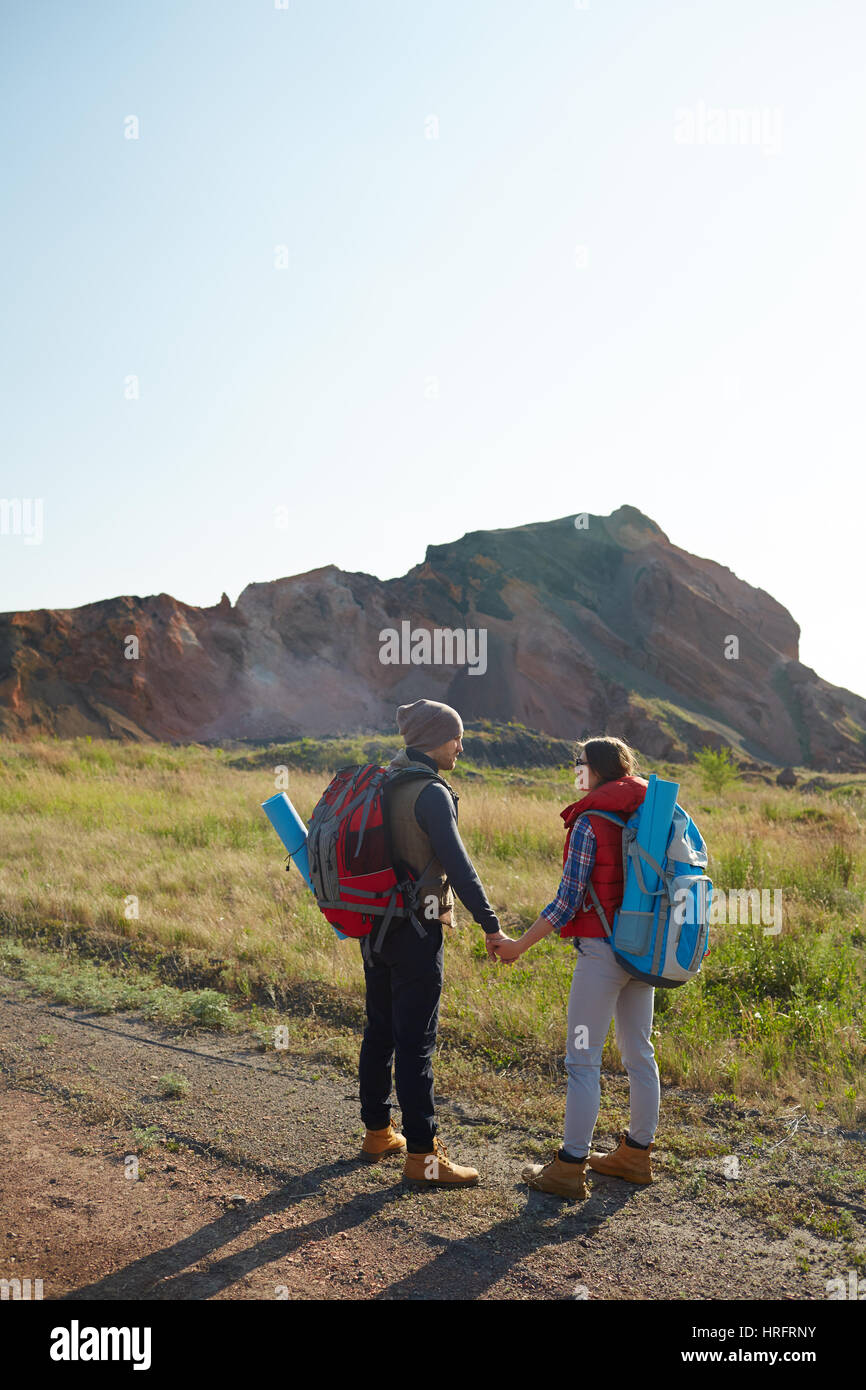 Back view portrait of young couple traveling together in mountains ...