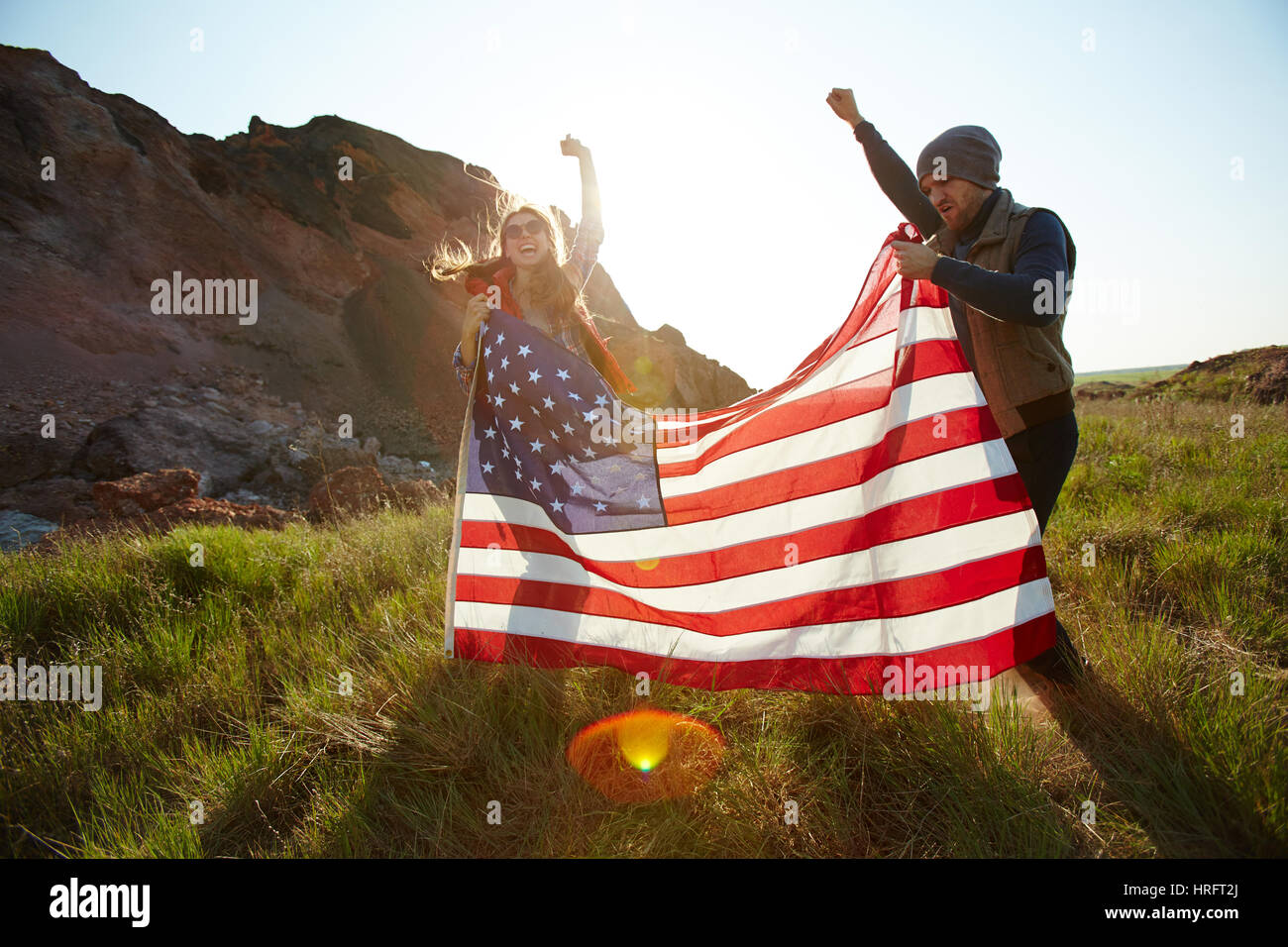 Couple of young people jumping and shouting loudly raising hands up ...