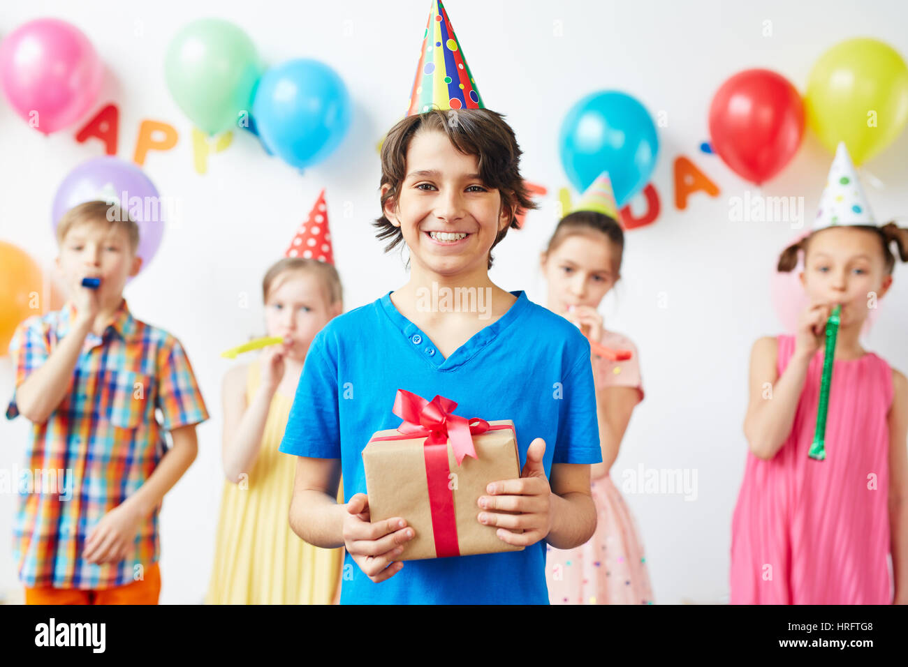 Portrait of excited birthday boy holding box with present standing in ...
