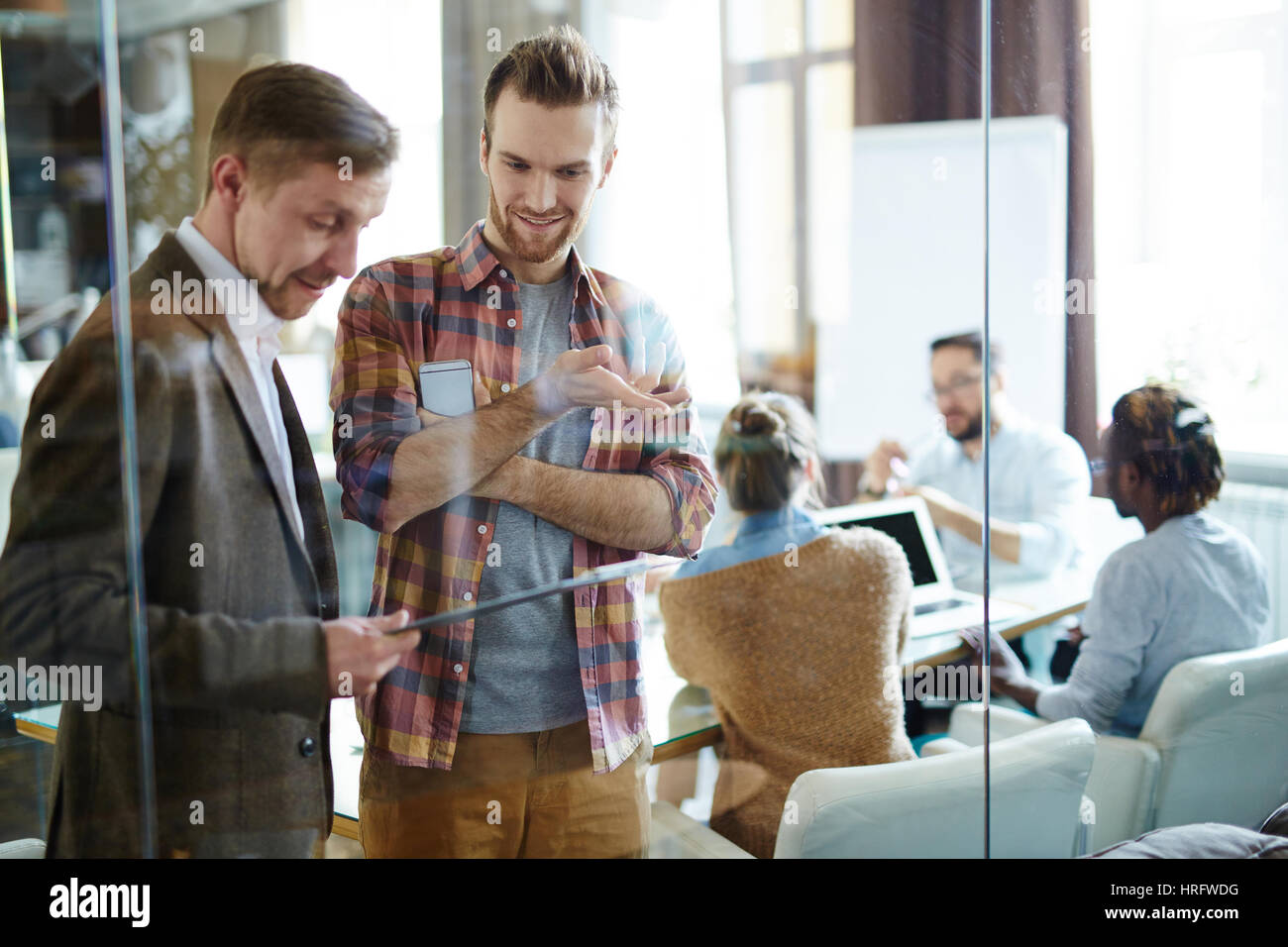 Handsome young employee and his middle-aged superior looking at ...