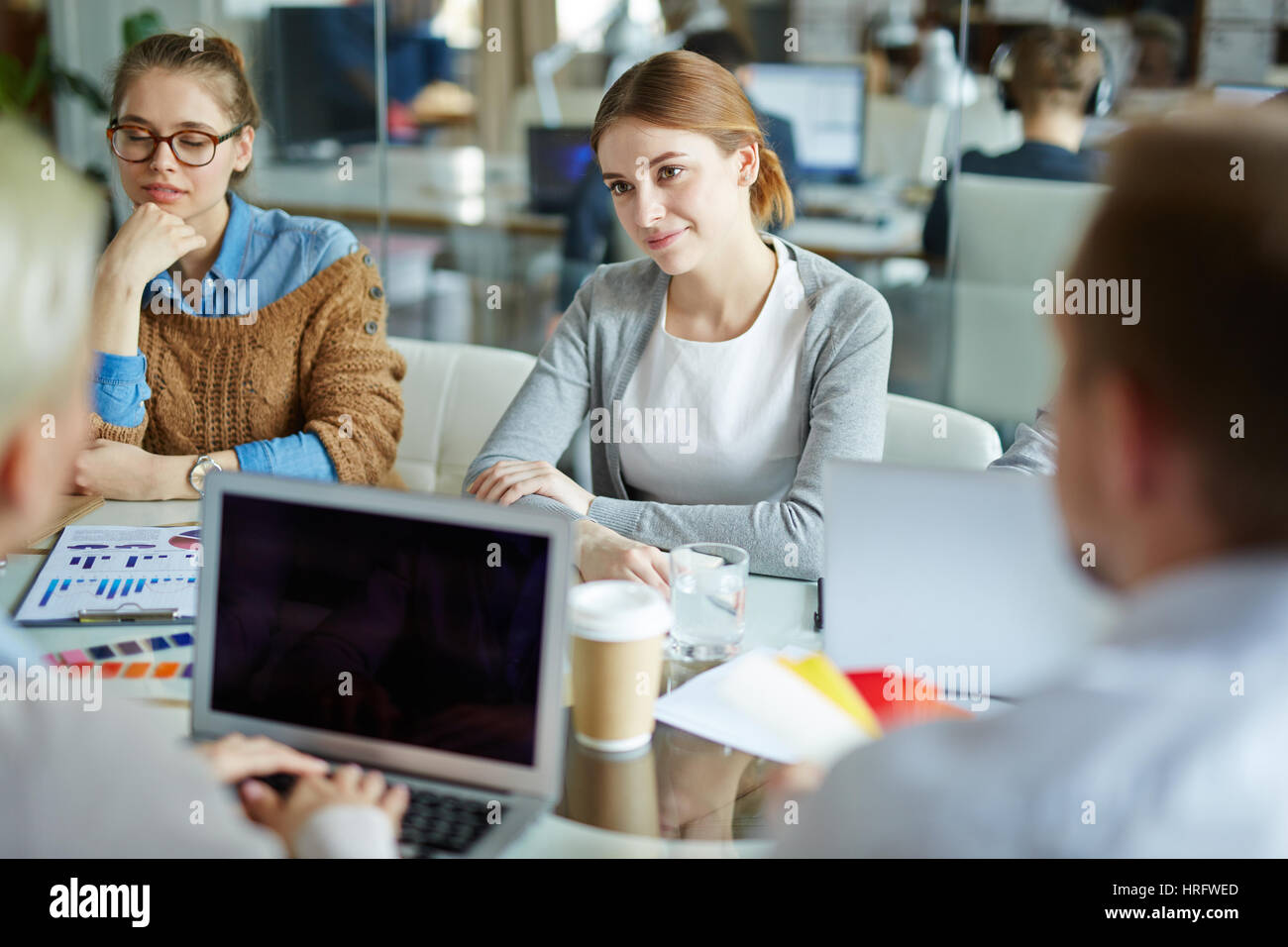 Productive negotiations in boardroom: pretty young clients sitting at ...