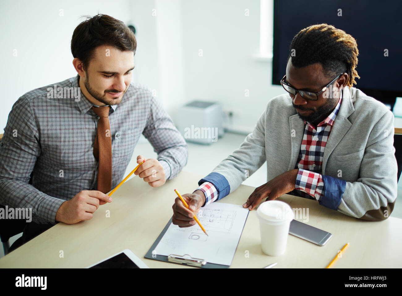 Afro-American programmer with short dreadlocks and his bearded coworker ...