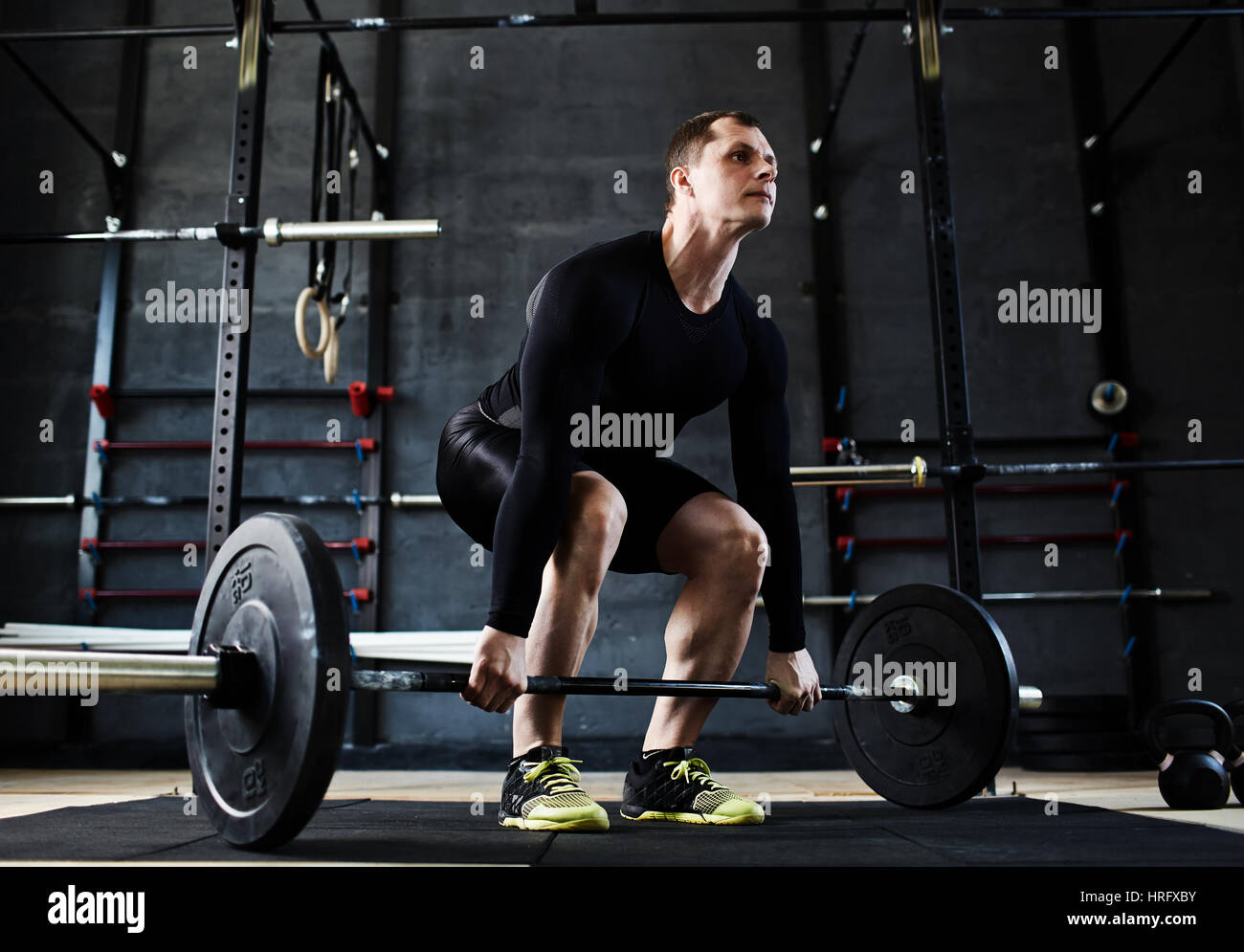 Low angle view of muscular male athlete lifting heavy barbell from ...