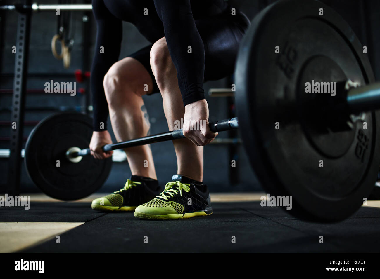 Low section of unrecognizable male athlete lifting huge heavy barbell ...