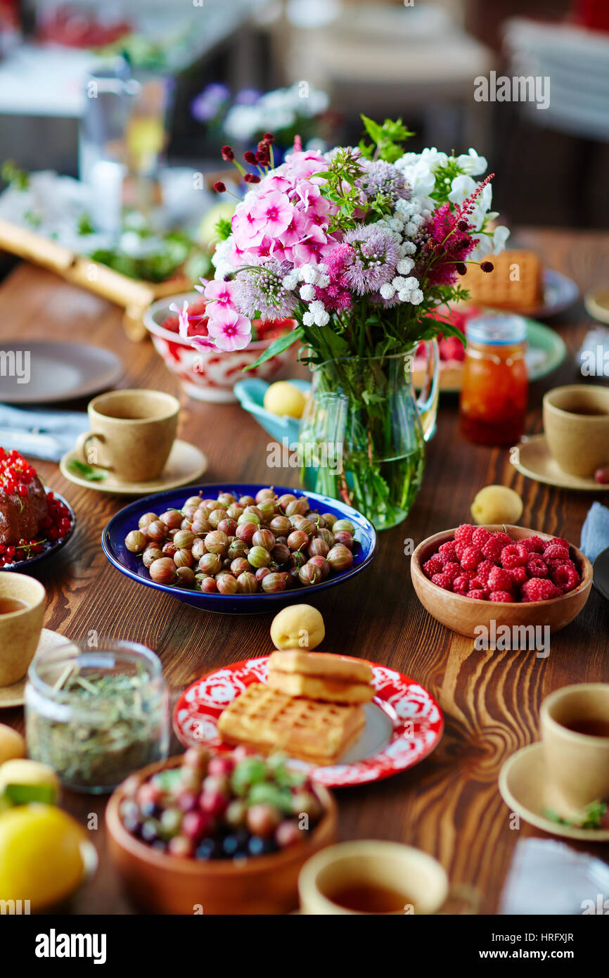 Seasonal table setting with fresh-cut field flowers, gooseberries and ...