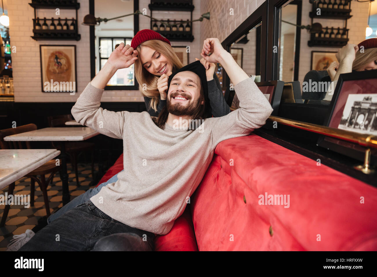 Couple in hats having fun on armchair in cafe Stock Photo - Alamy