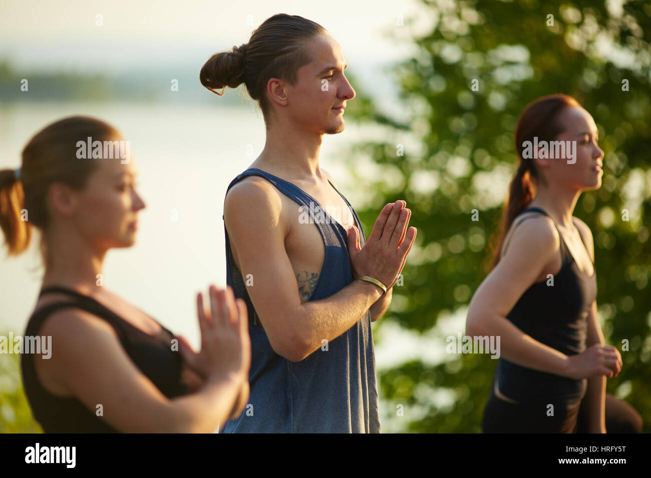 Close-up view of three friends holding hands in namaste while ...