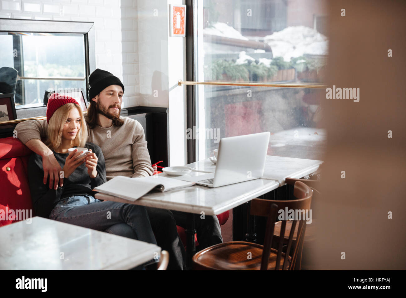 Side view of couple hugging and sitting by the table in cafe Stock ...