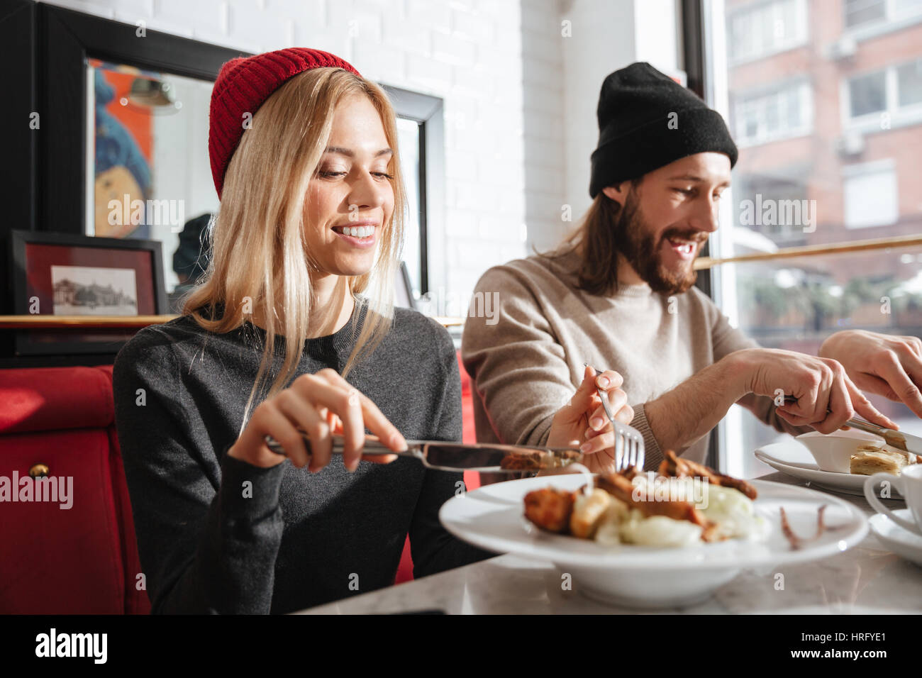 Side view of couple sitting by the table and eating in cafe Stock Photo ...