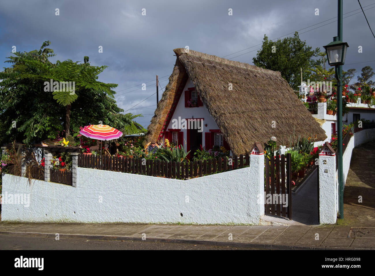 Old man sitting in the garden of traditional reed roof farmhouse ...